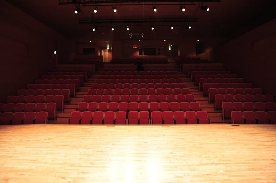 Empty theatre interior with red seats and illuminated stage