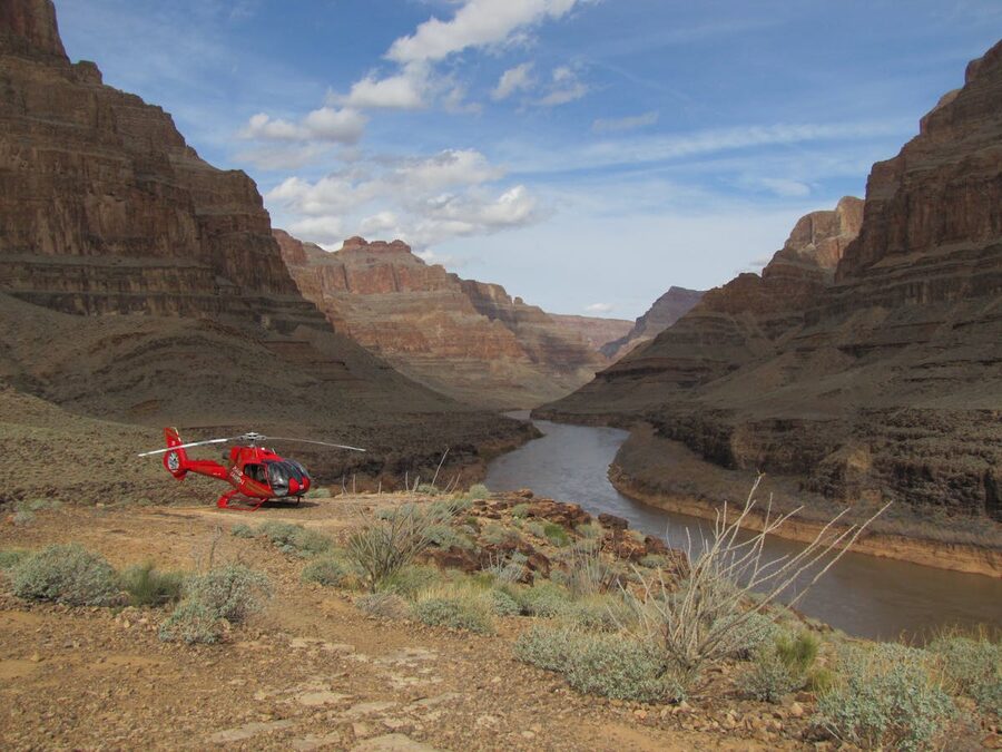 Red helicopter landed at the bottom of Grand Canyon near the Colorado River