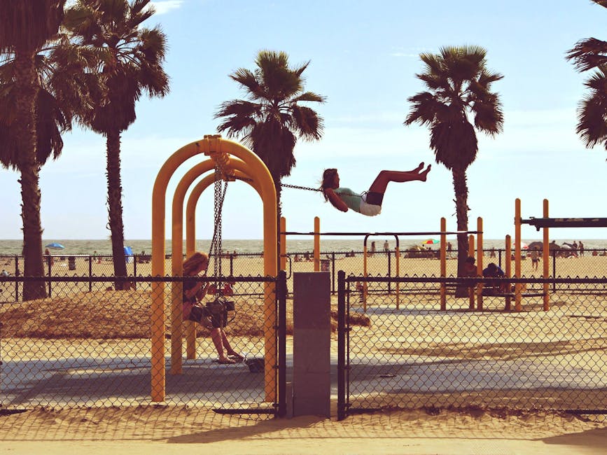 Kids playing on swings among palm trees at Venice Beach