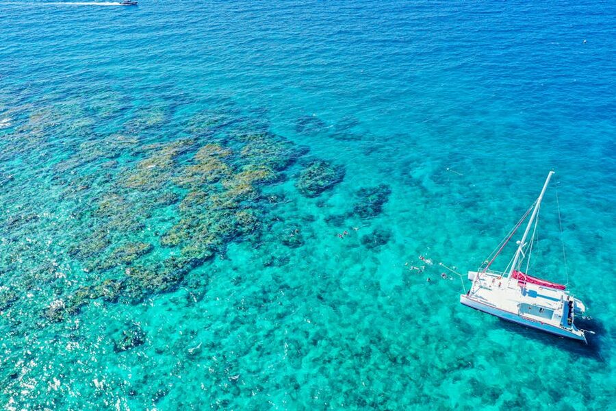 Catamaran sailing over a turquoise reef in the Coral Sea