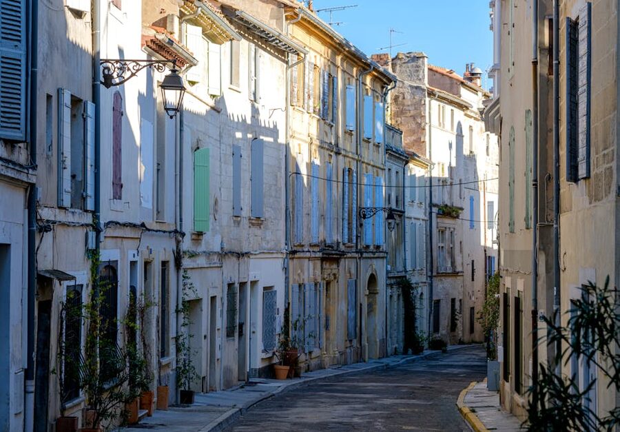 Sunlit narrow street in Arles France with rustic architecture