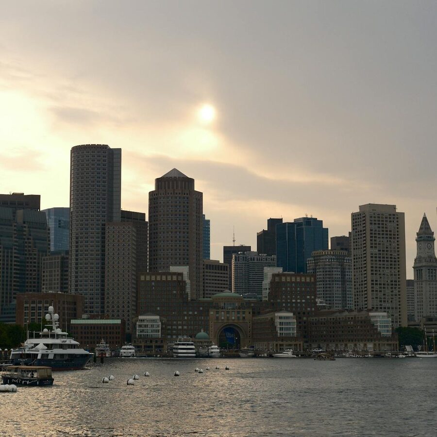 Boston skyline and harbor at dusk with a cargo ship in the foreground