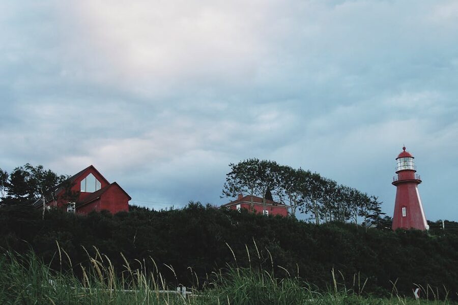 Red lighthouse on Ile d Orleans with cottages and green grass Quebec City