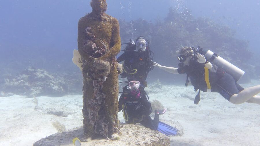 Scuba divers exploring sculptures at the MUSA underwater museum