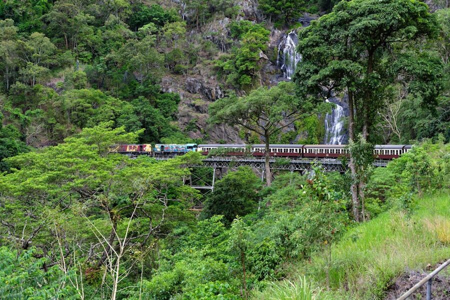 Kuranda Scenic Railway train crossing a waterfall bridge in the rainforest