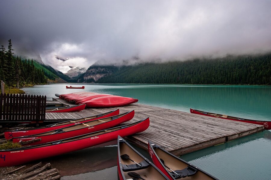Red canoes lined up on turquoise Lake Louise shoreline