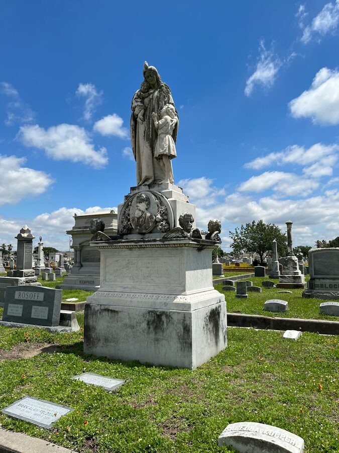 Marble statue in a cemetery with a clear blue sky above