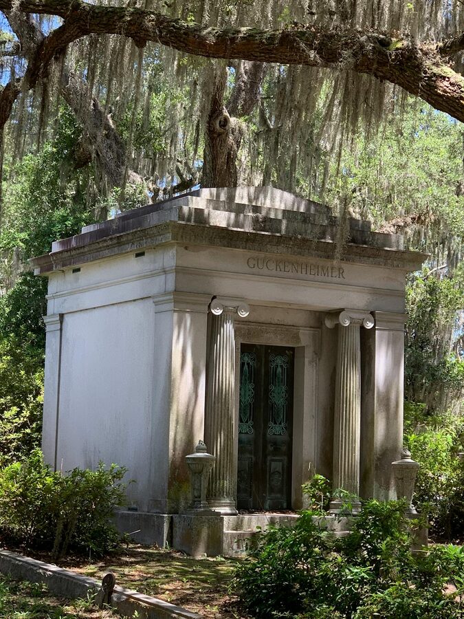 Elegant mausoleum surrounded by moss draped trees in a cemetery