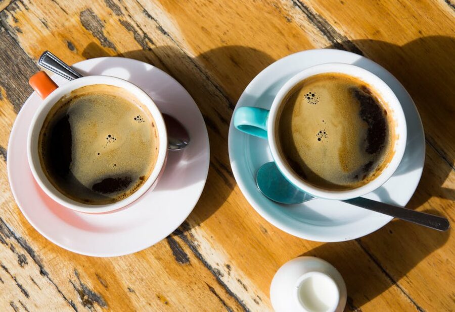 Two coffee cups on a wooden cafe table top down view
