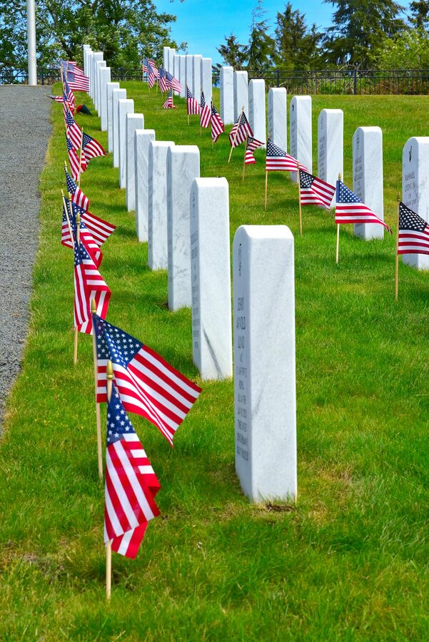 Rows of gravestones with American flags in a military cemetery