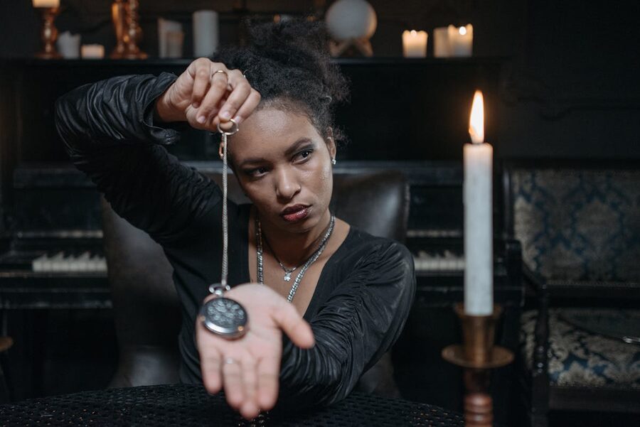 Woman performing hypnosis with pocket watch candlelight