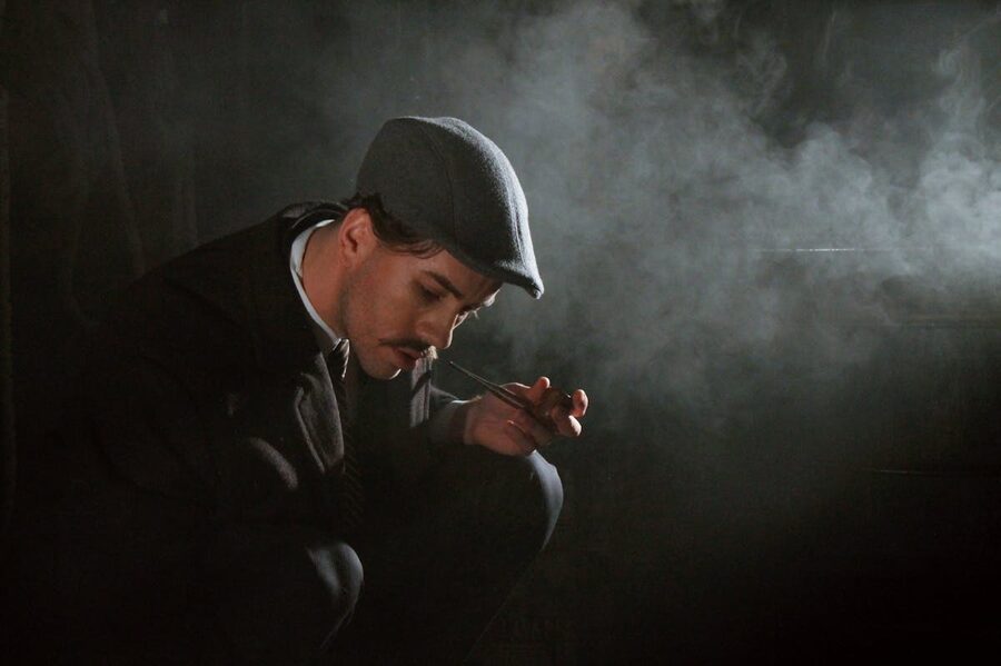 Man in vintage attire smoking pipe in dark moody noir setting
