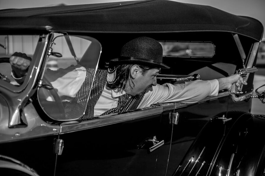 Vintage 1930s gangster aiming pistol black and white dramatic