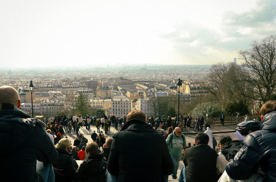 People enjoying panoramic view of Paris from Sacre Coeur steps Montmartre