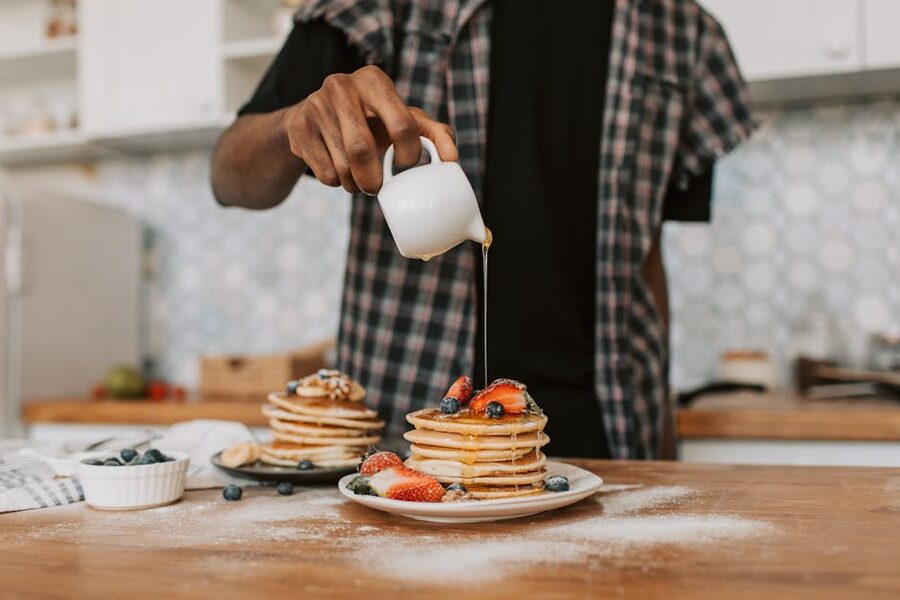 Pouring maple syrup over pancakes