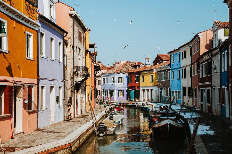 Colorful houses along Venice canal with gondolas Burano