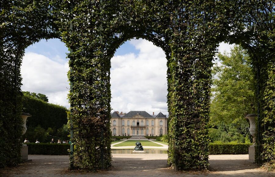 View of the Hotel Biron mansion through a leafy archway in the Musee Rodin garden Paris