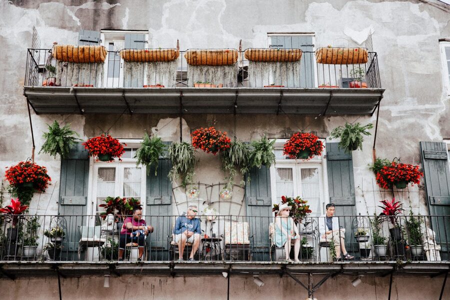 People relaxing on a New Orleans balcony with colorful floral decorations