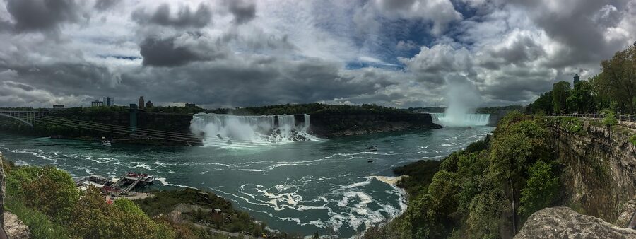 Panorama of Niagara Falls showing US and Canadian sides with tour boat