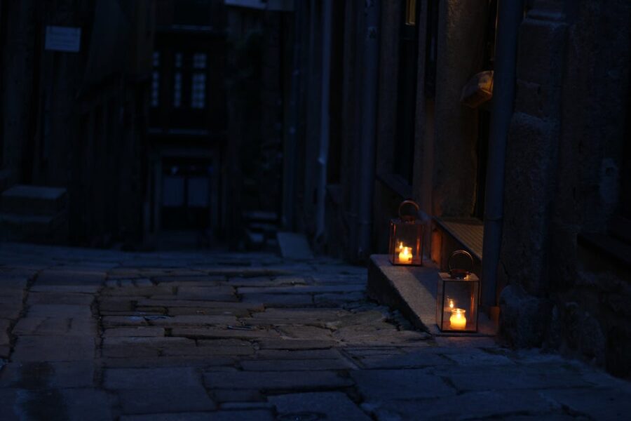 Dimly lit cobblestone alley with warm glowing lanterns at night