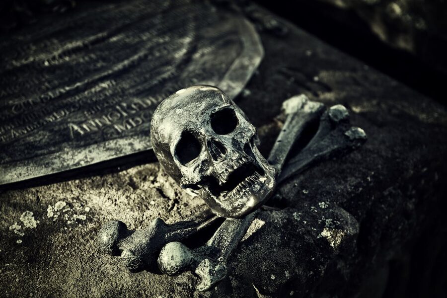 Skull and crossbones on ancient tombstone haunting cemetery