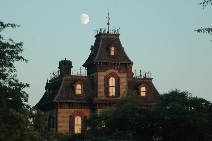 Victorian mansion under twilight sky with crescent moon