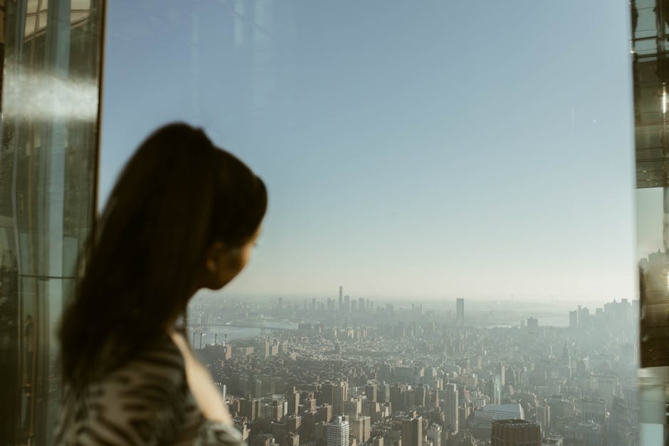 Woman viewing NYC skyline from a high-rise window