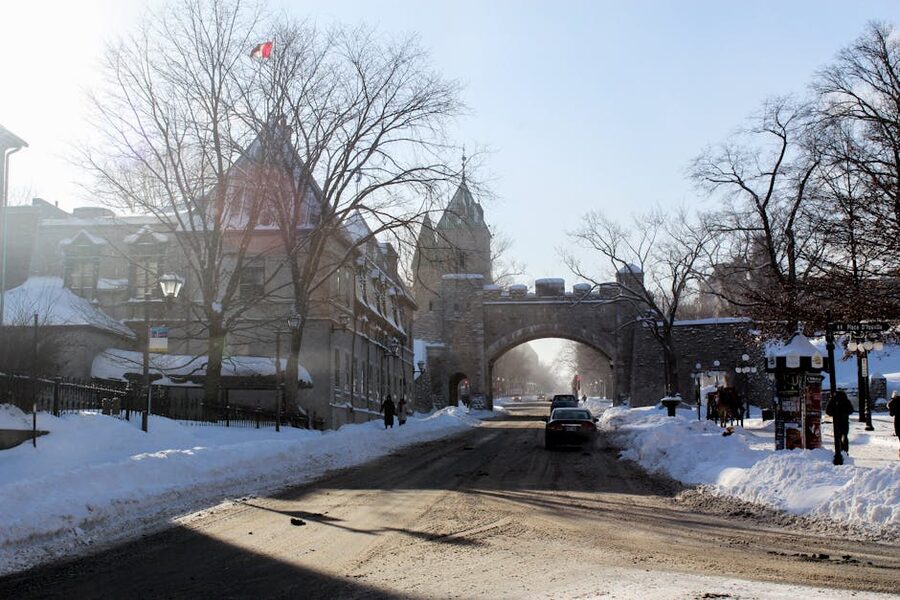 Snow-covered street with historic stone gate in Old Quebec winter