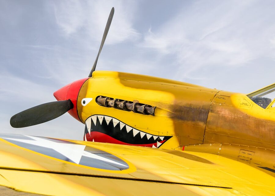 Yellow P-40 Warhawk aircraft with propeller and shark mouth nose art