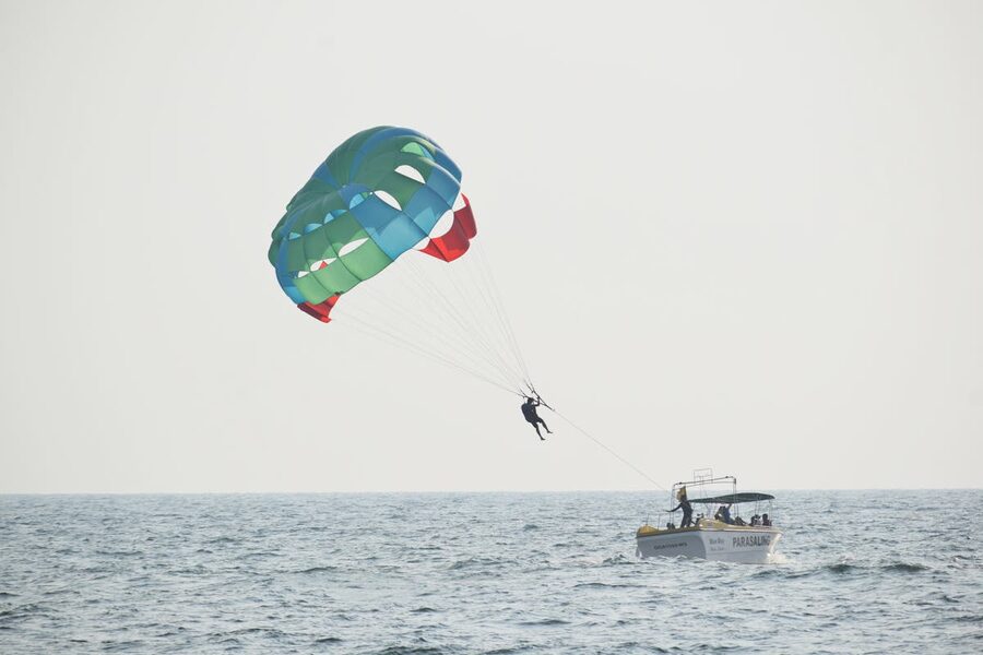 Parasailing over the sea with a colorful parachute pulled by a speedboat