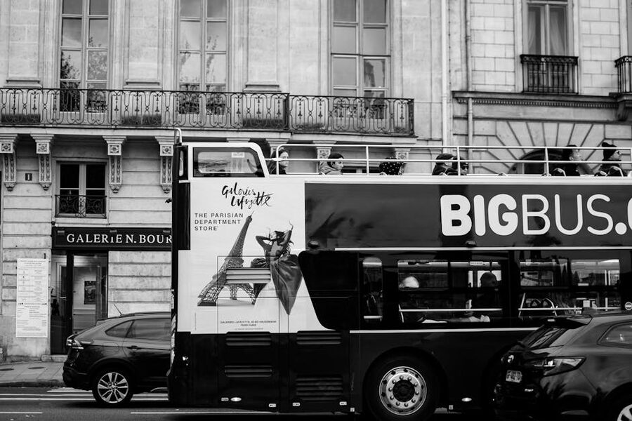 Double decker tour bus passing Galeries Lafayette Paris in black and white