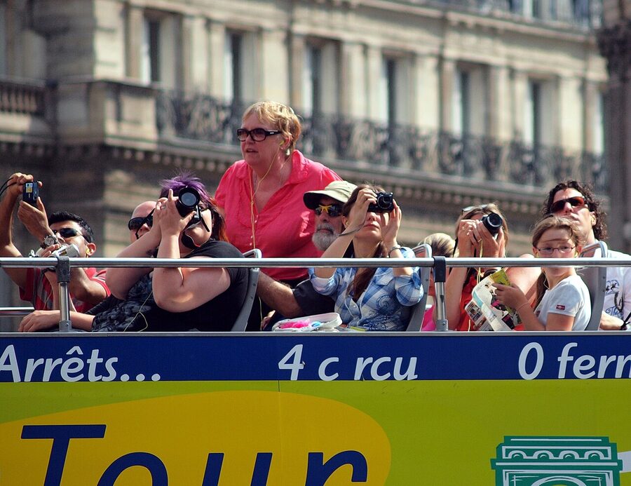 Tourists on top deck of an open top hop on hop off bus tour Paris