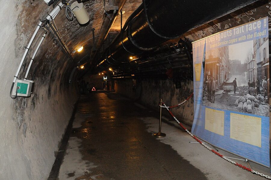 Visitor walkway running alongside an active sewer channel inside the Paris Sewer Museum