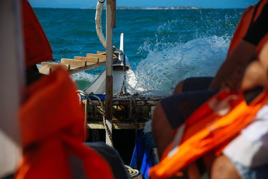Passenger in a life vest on an open boat with ocean spray