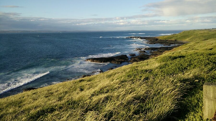 Waves crashing against the green cliffs of Phillip Island