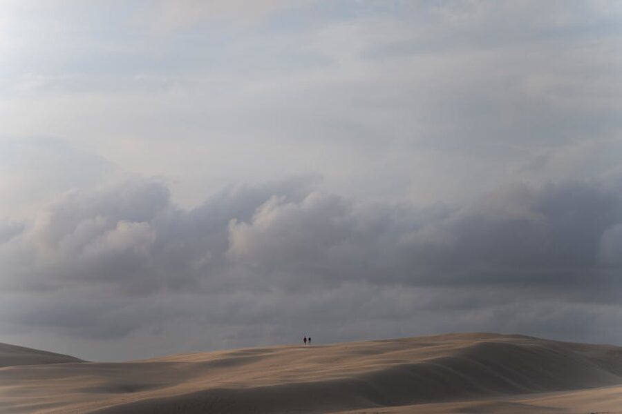 Two figures crossing the Stockton sand dunes near Port Stephens