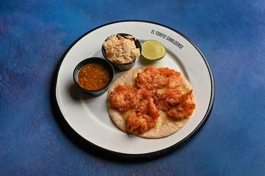 Crispy shrimp taco with coleslaw, salsa and lime