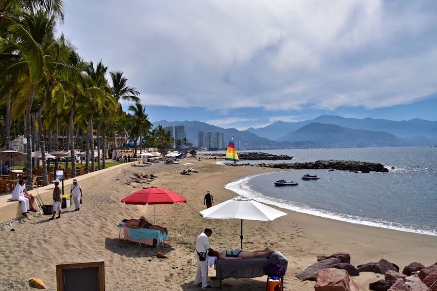 Puerto Vallarta beach with palm trees and sailboat