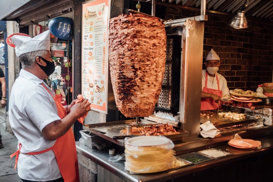 Street vendor serving tacos al pastor from a vertical trompo spit in Puerto Vallarta