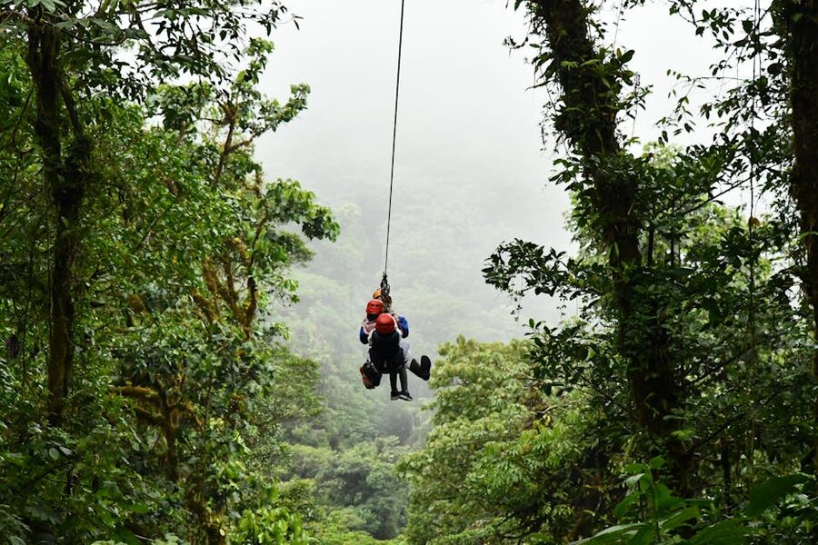 Two people on a zipline in lush jungle