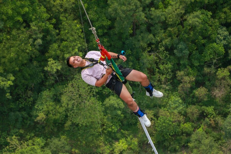 Man smiling while ziplining over dense forest