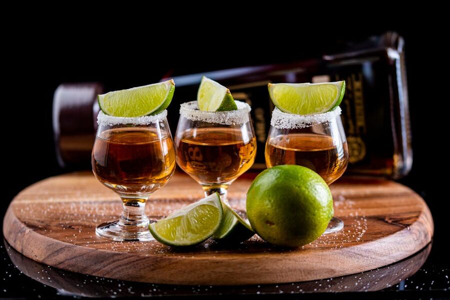 Tequila tasting flight on a wooden board with lime wedges