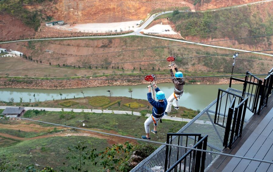 Two people on a zipline over a valley