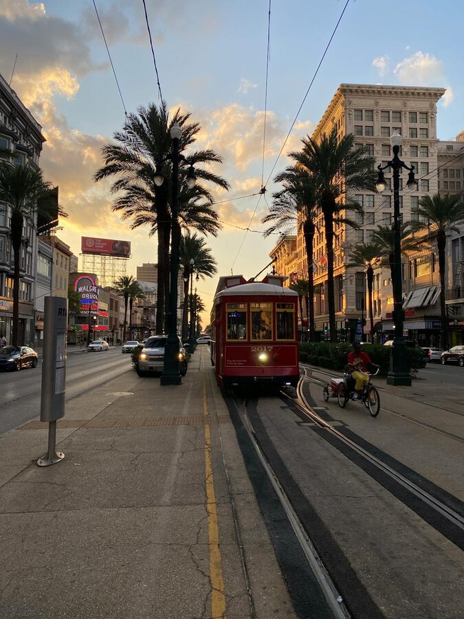 Classic red streetcar gliding through downtown New Orleans at sunset