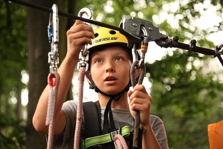 Young guest with a helmet and harness ready for a zipline tour