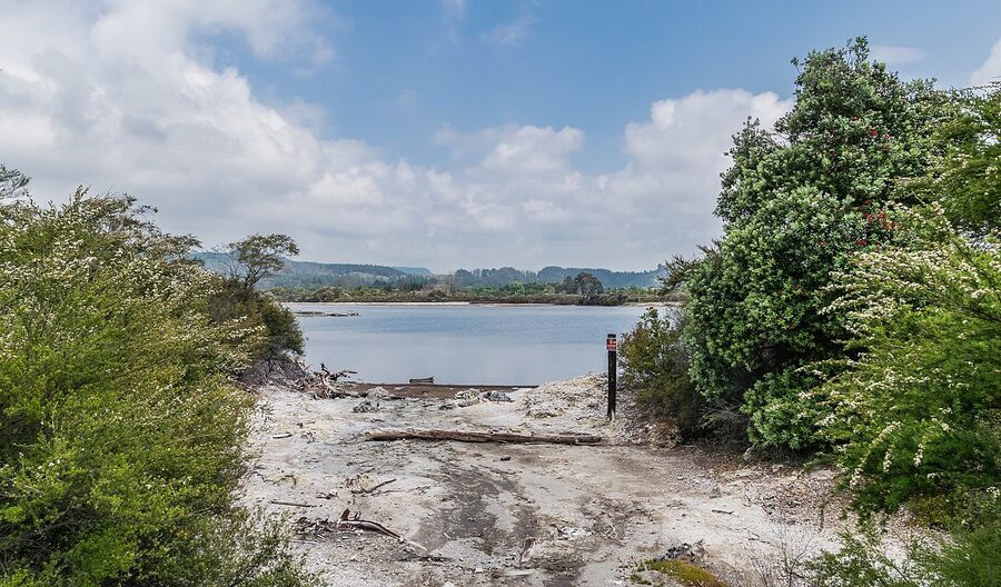 Lake Rotorua waterfront view with Maori buildings and steam