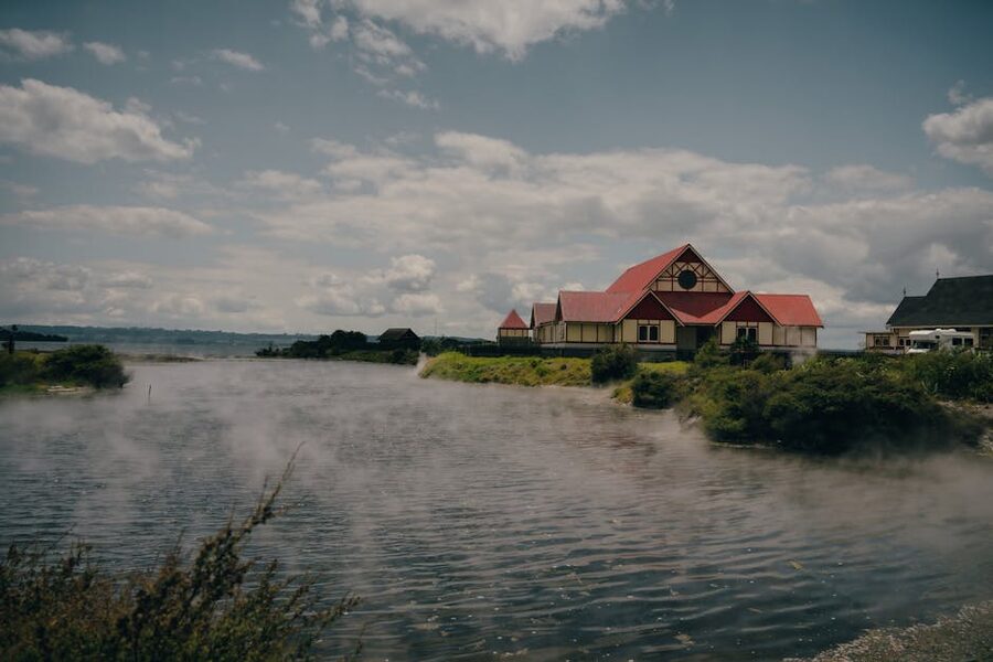 Traditional Maori building beside Lake Rotorua with rising steam