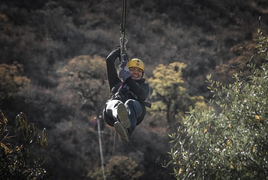 Zipline rider in helmet and harness on cable