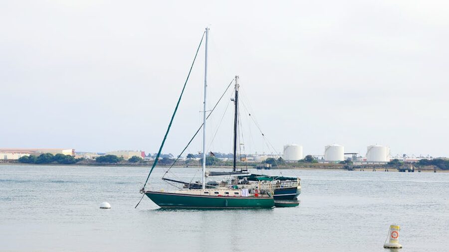 Sailboats in San Diego Harbor with industrial tanks in the background