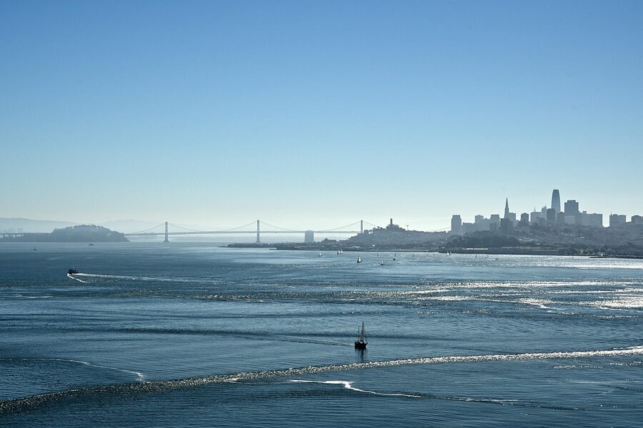 San Francisco Bay Bridge and skyline at sunset with a ship passing